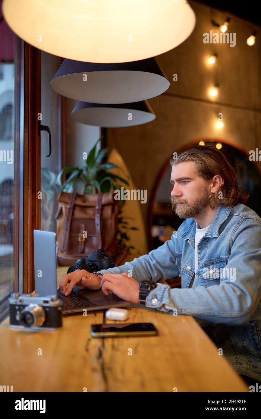 Confident caucasian male photographer working at desktop with laptop ...