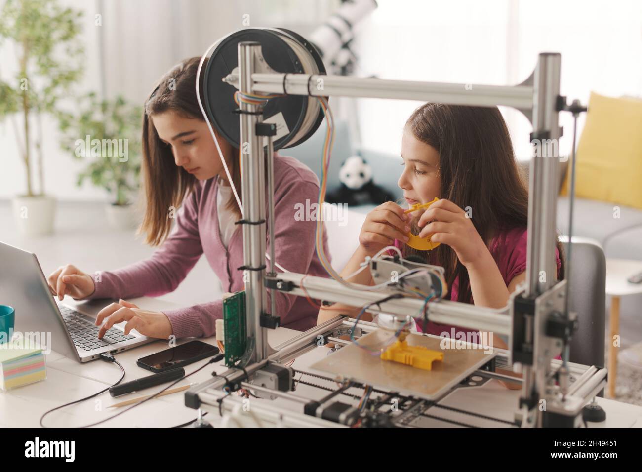 Young smart girls learning 3D printing at home, they are using a 3D ...
