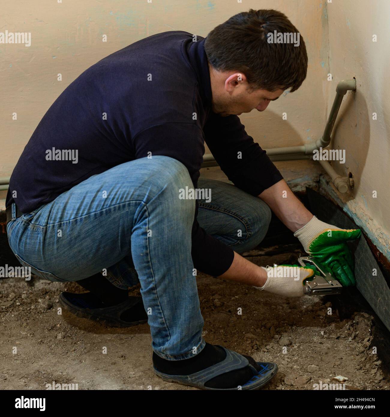 The worker attaches a bitumen tape with a stapler to protect the wood ...