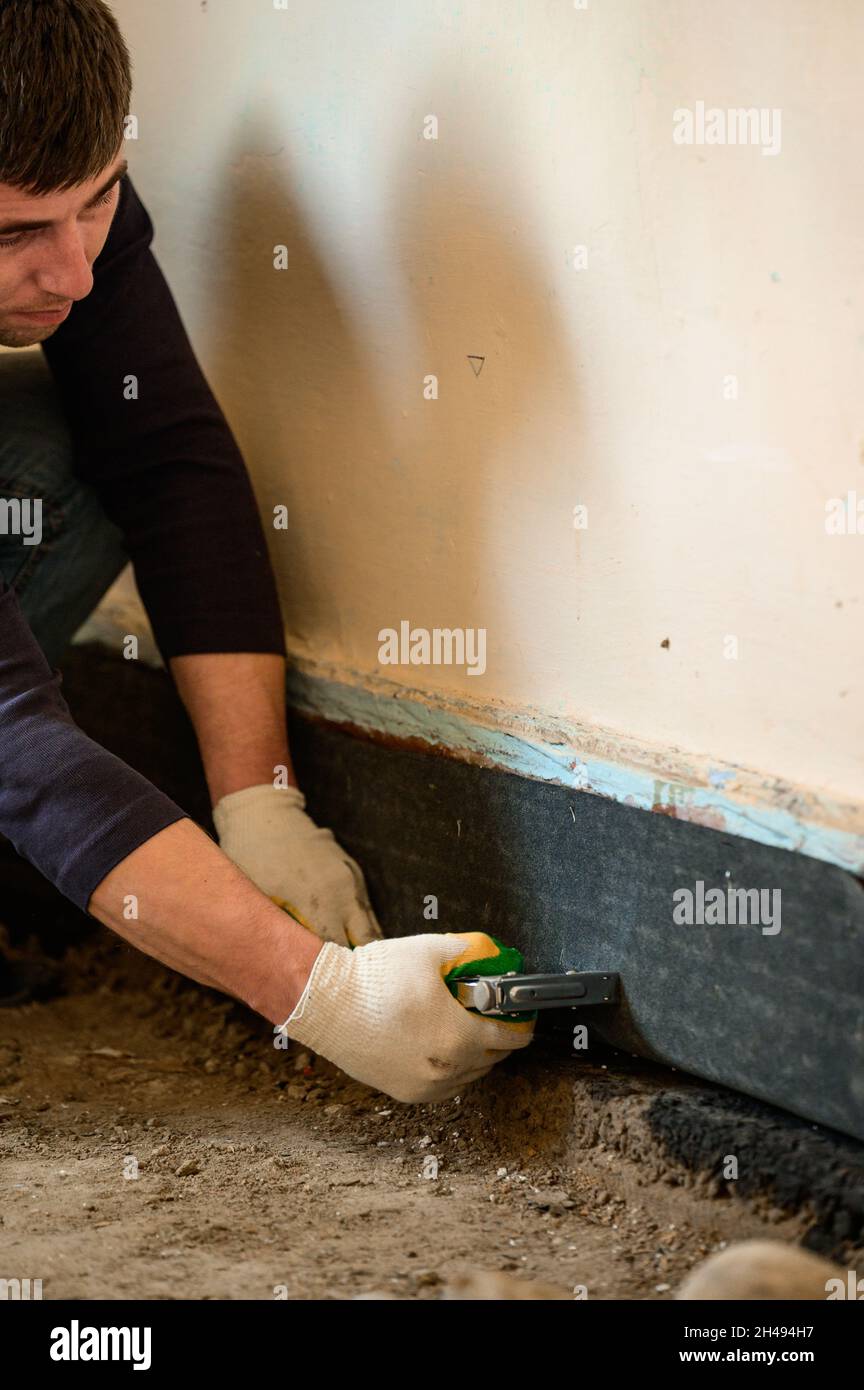 Installing waterproofing in a private house on the floor, a man ...