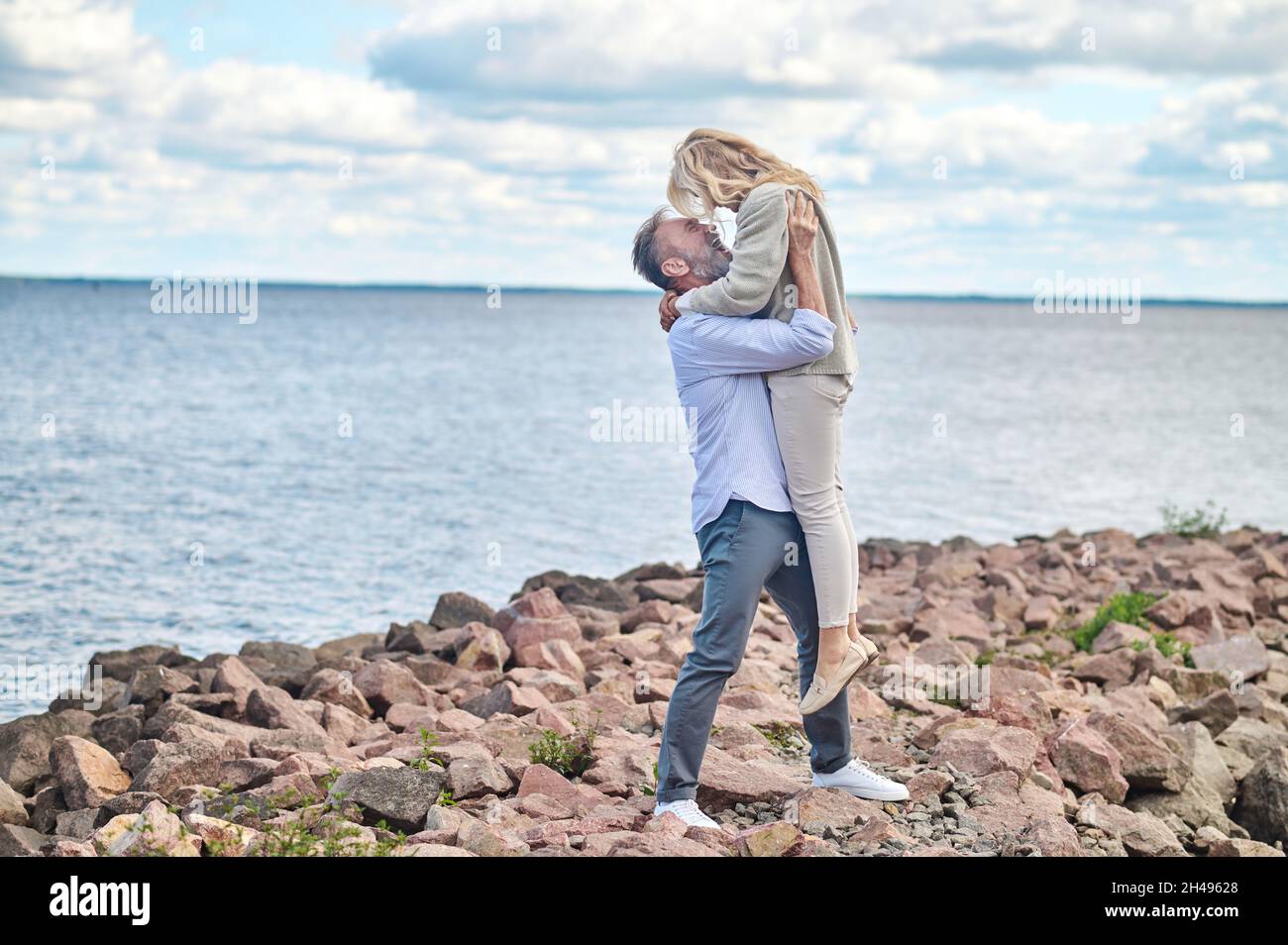Man raising joyful woman in his arms Stock Photo - Alamy
