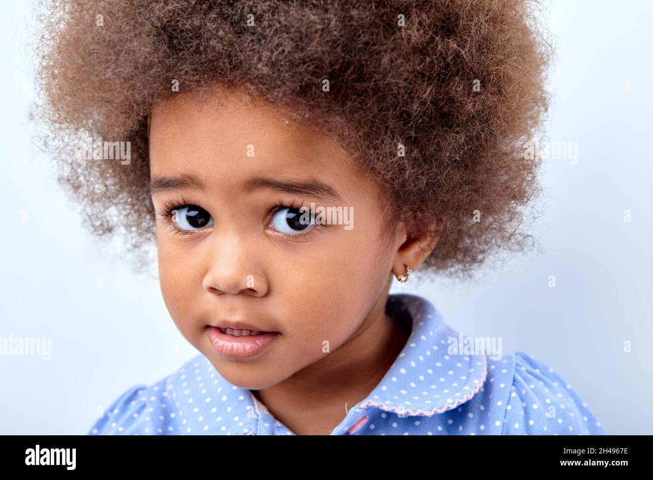 Cute multiracial small girl with funny expression look at camera ...