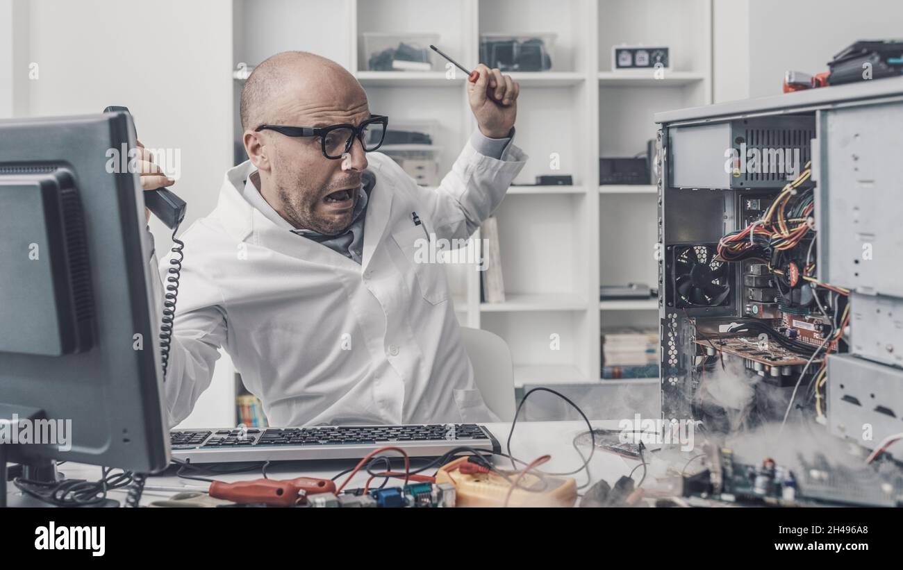 Burning computer on the technician desk, he is shocked and scared Stock ...