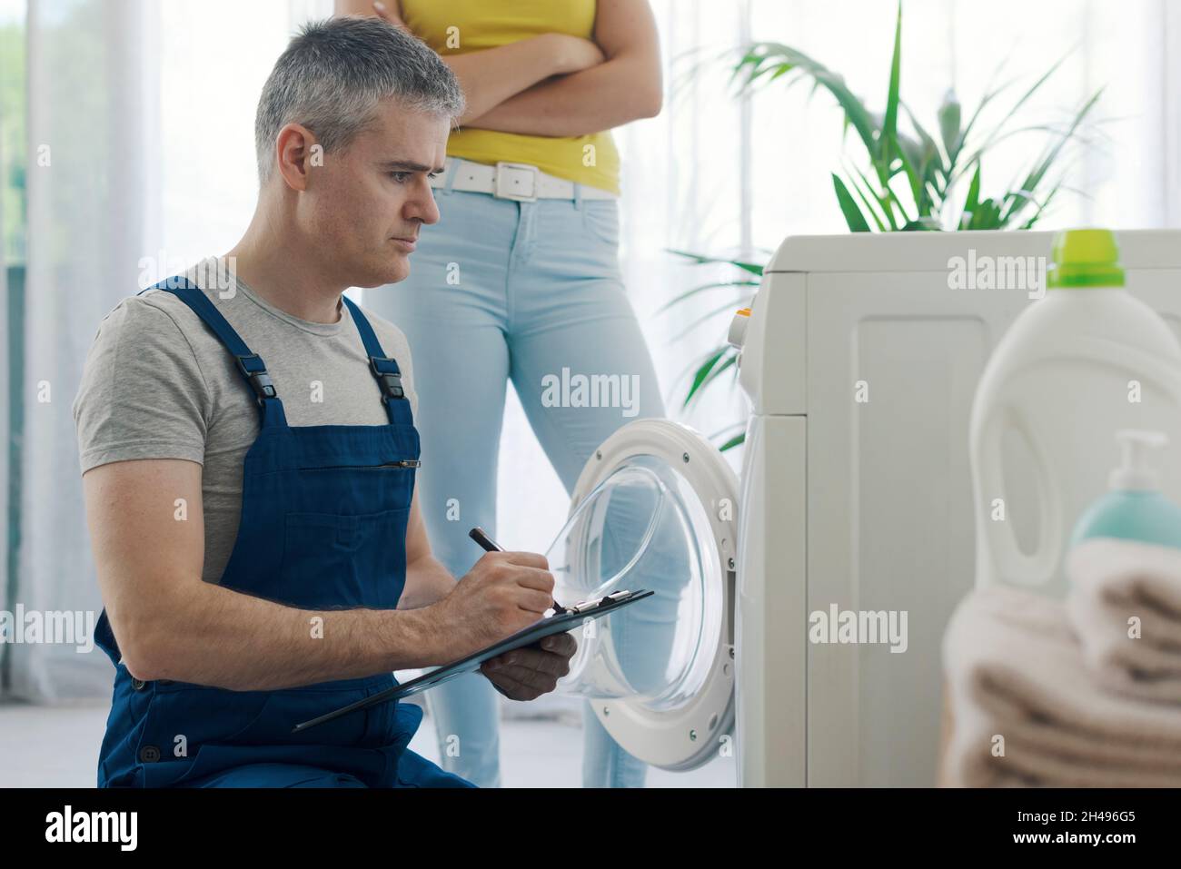 Technician performing a check-up on a washing machine, he is writing on ...