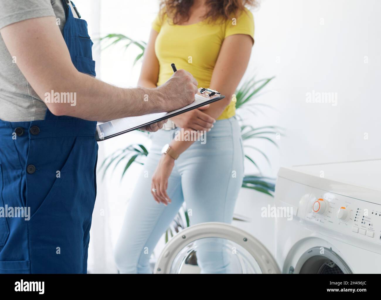 Technician performing a check-up on a washing machine, he is writing on ...