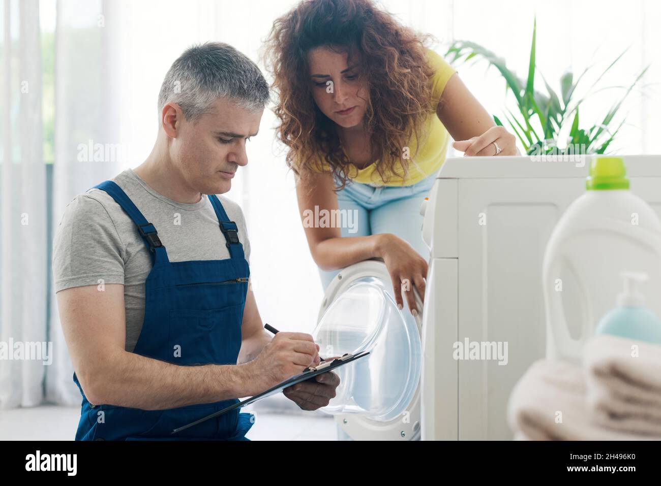 Technician performing a check-up on a washing machine, he is writing on ...