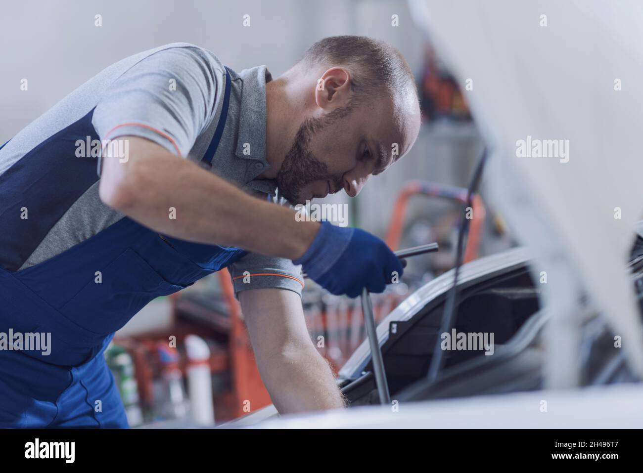 Mechanic fixing a car engine in the auto repair shop Stock Photo - Alamy