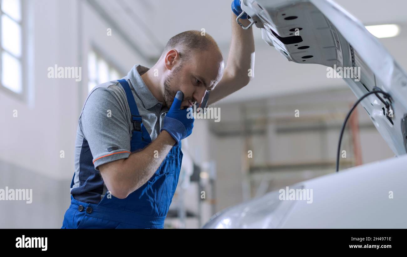 Professional mechanic doing a car inspection and checking the engine ...