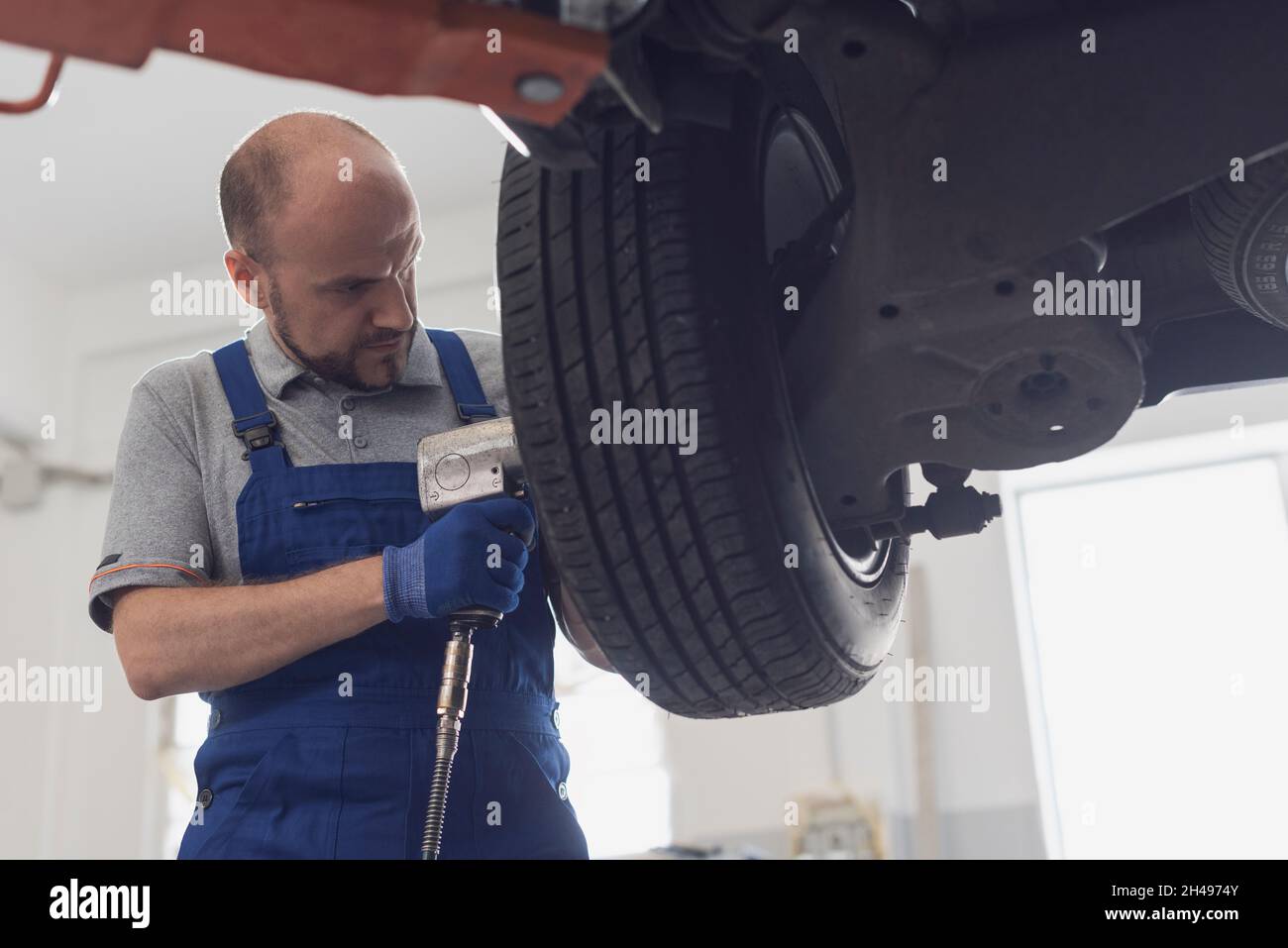 Professional mechanic doing a wheel replacement on a lifted car using a ...