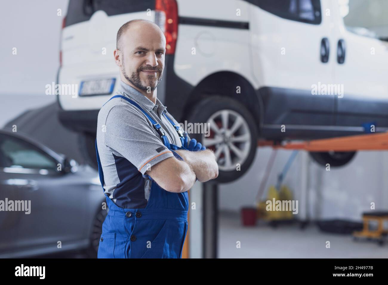 Confident smiling mechanic posing in the auto repair shop, car service ...