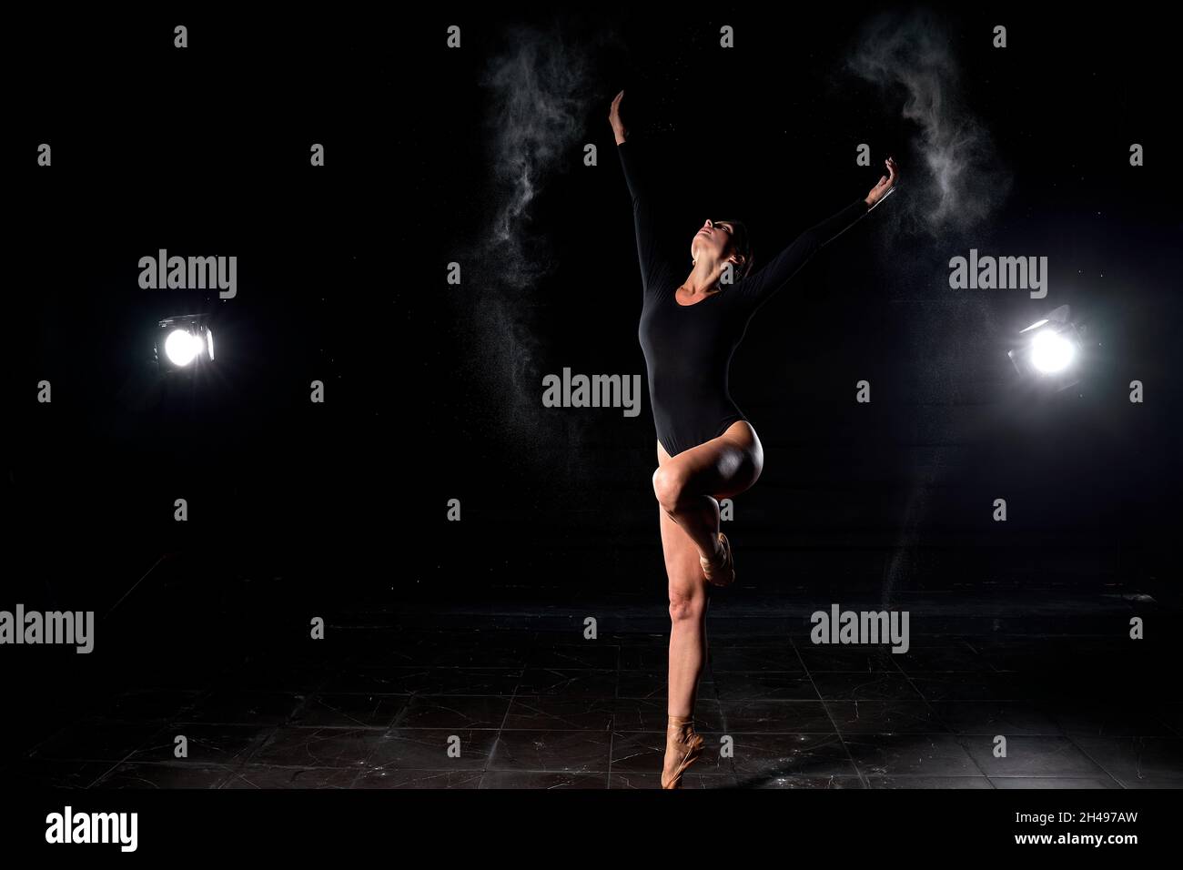Ballerina dancing with flour on black studio background. Dancer in ...