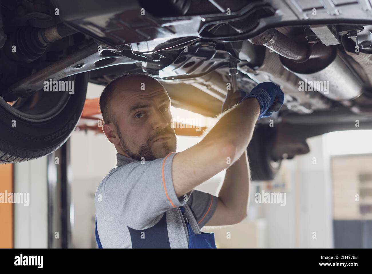 Professional mechanic working under a car, he is doing a vehicle ...