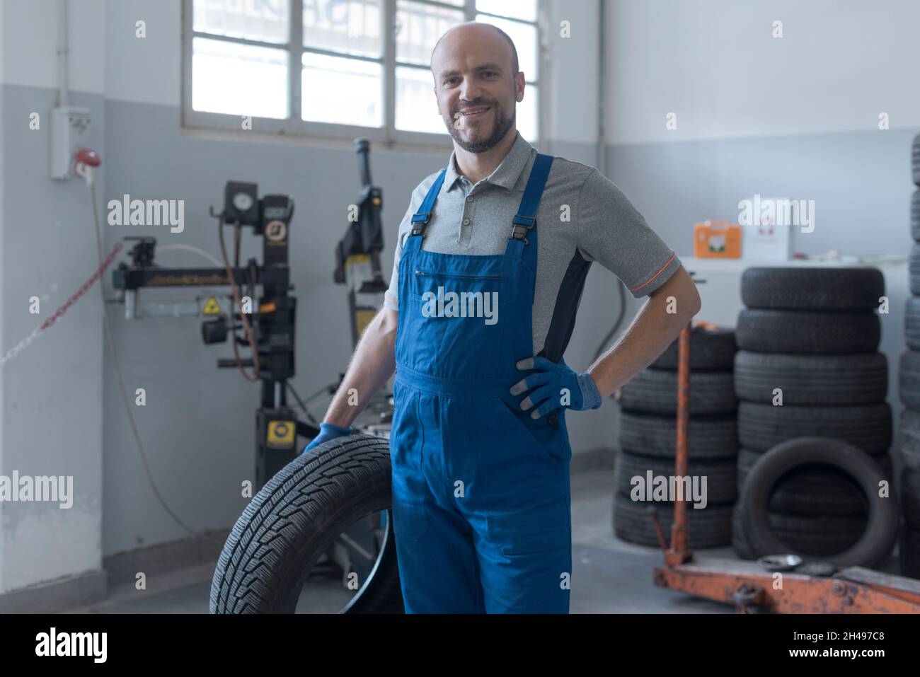 Professional smiling mechanic posing in the auto repair station, he is ...