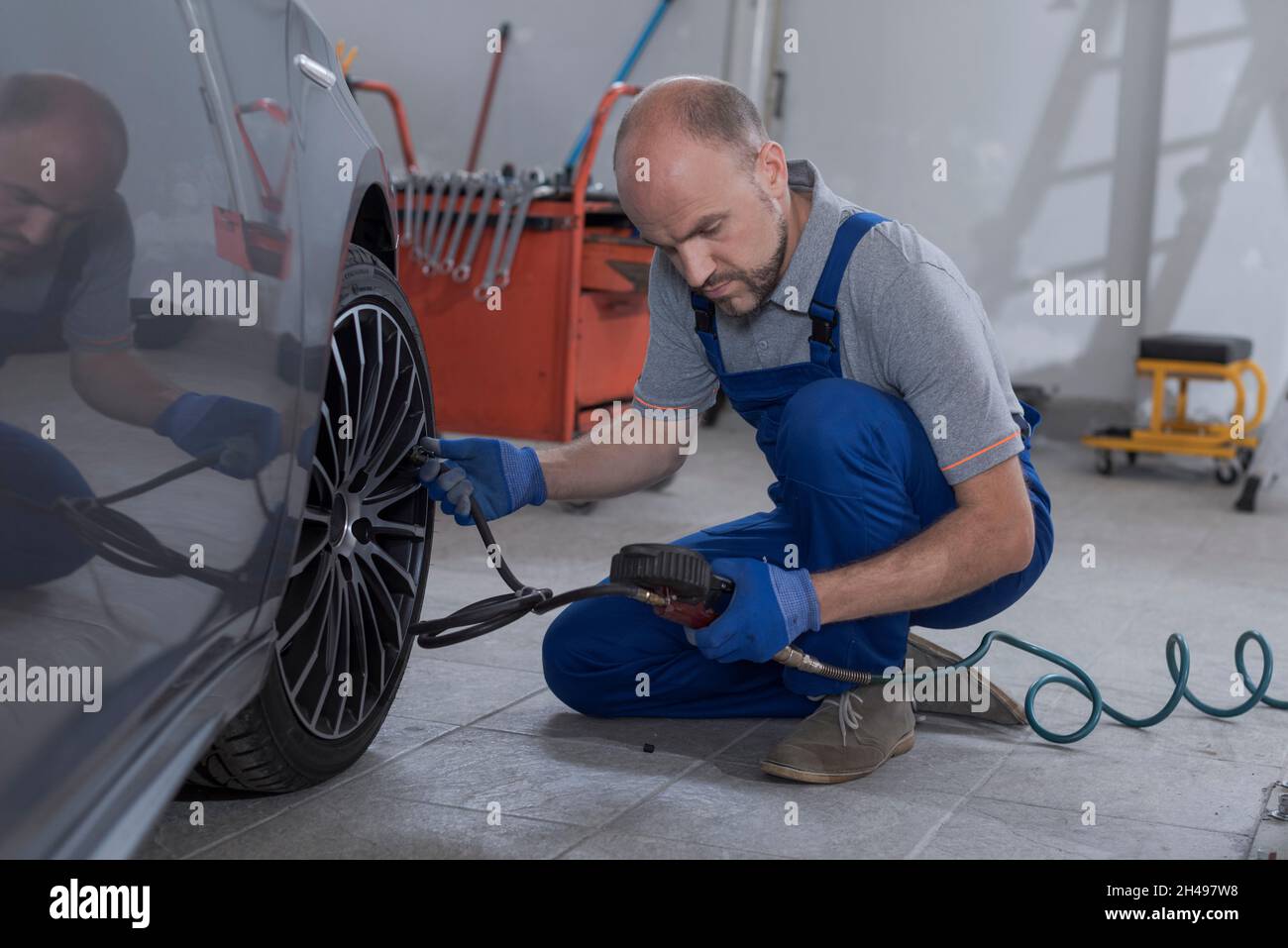 Mechanic inflating a tire and checking air pressure with a pressure ...