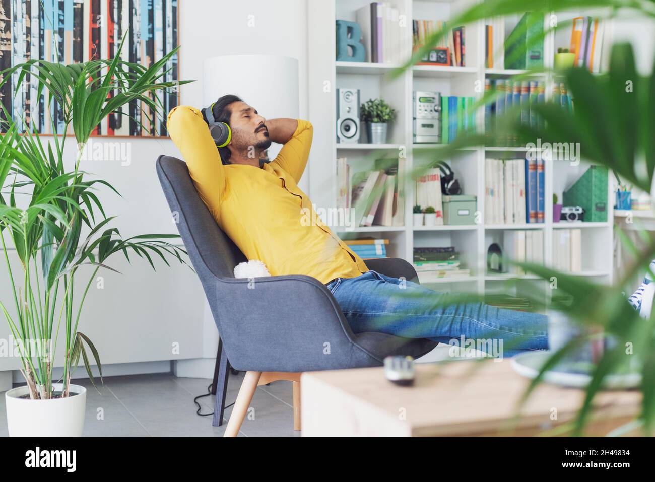 Young man relaxing in the living room at home and listening to music ...