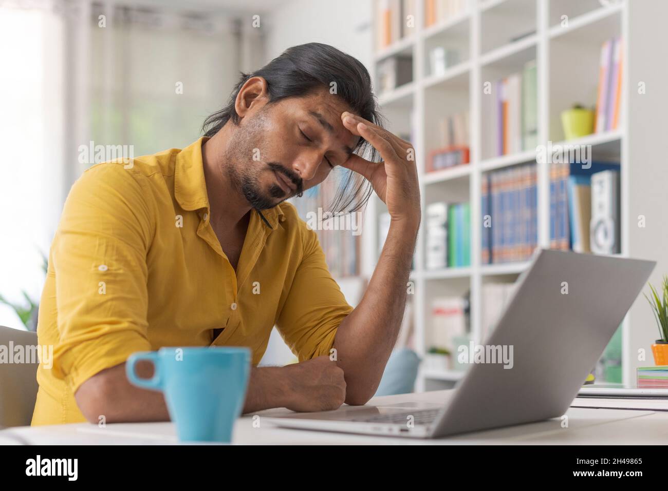 Young stressed man working with a laptop in his office at home, he is ...