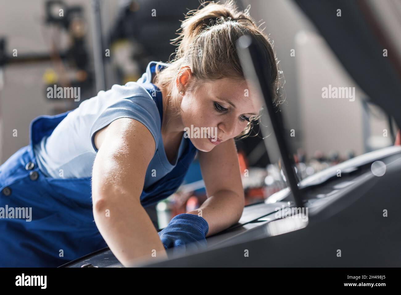 Professional female mechanic working in the auto repair shop, she is ...