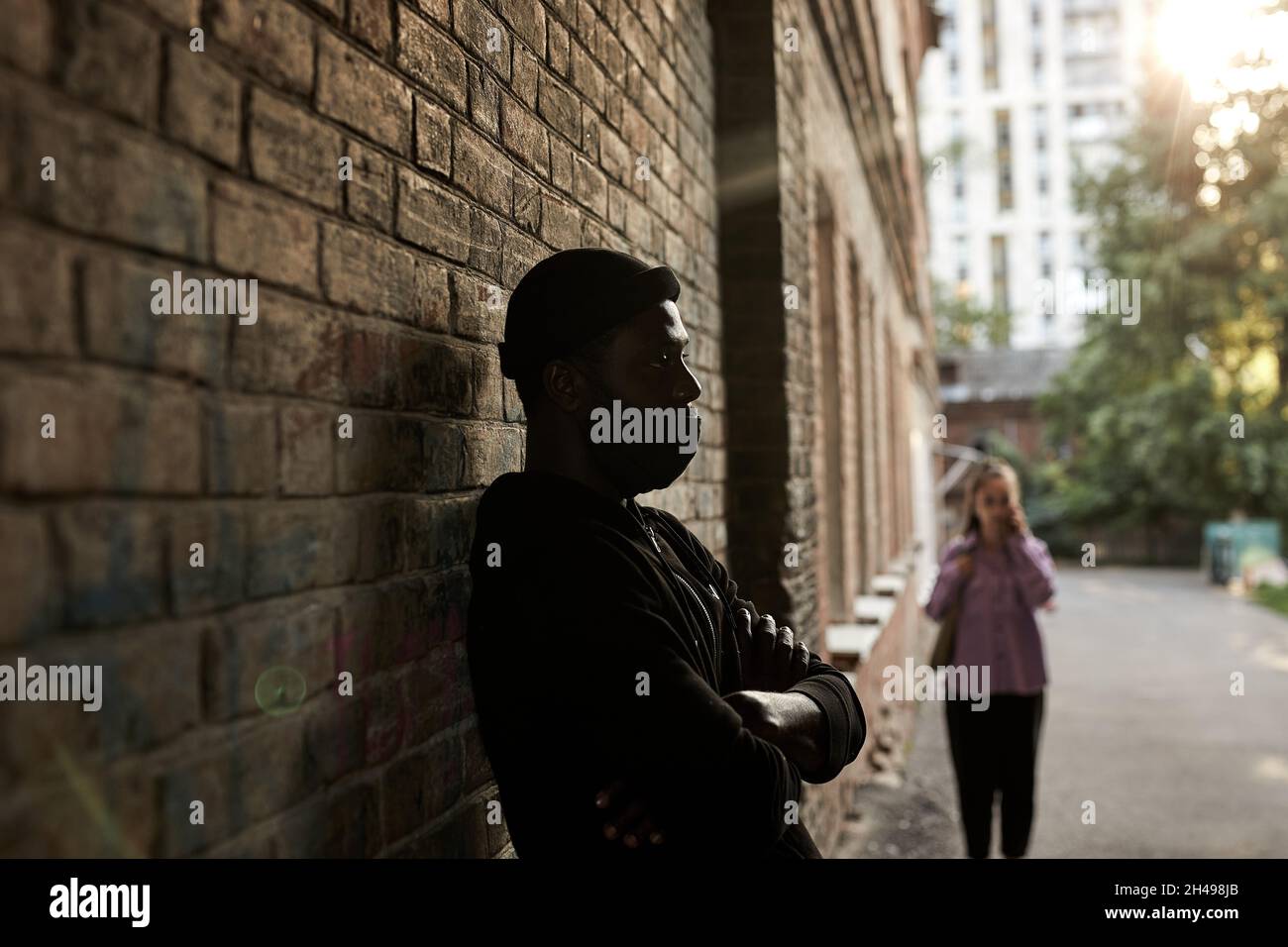 criminal is standing at street waiting for female victim, side view on ...