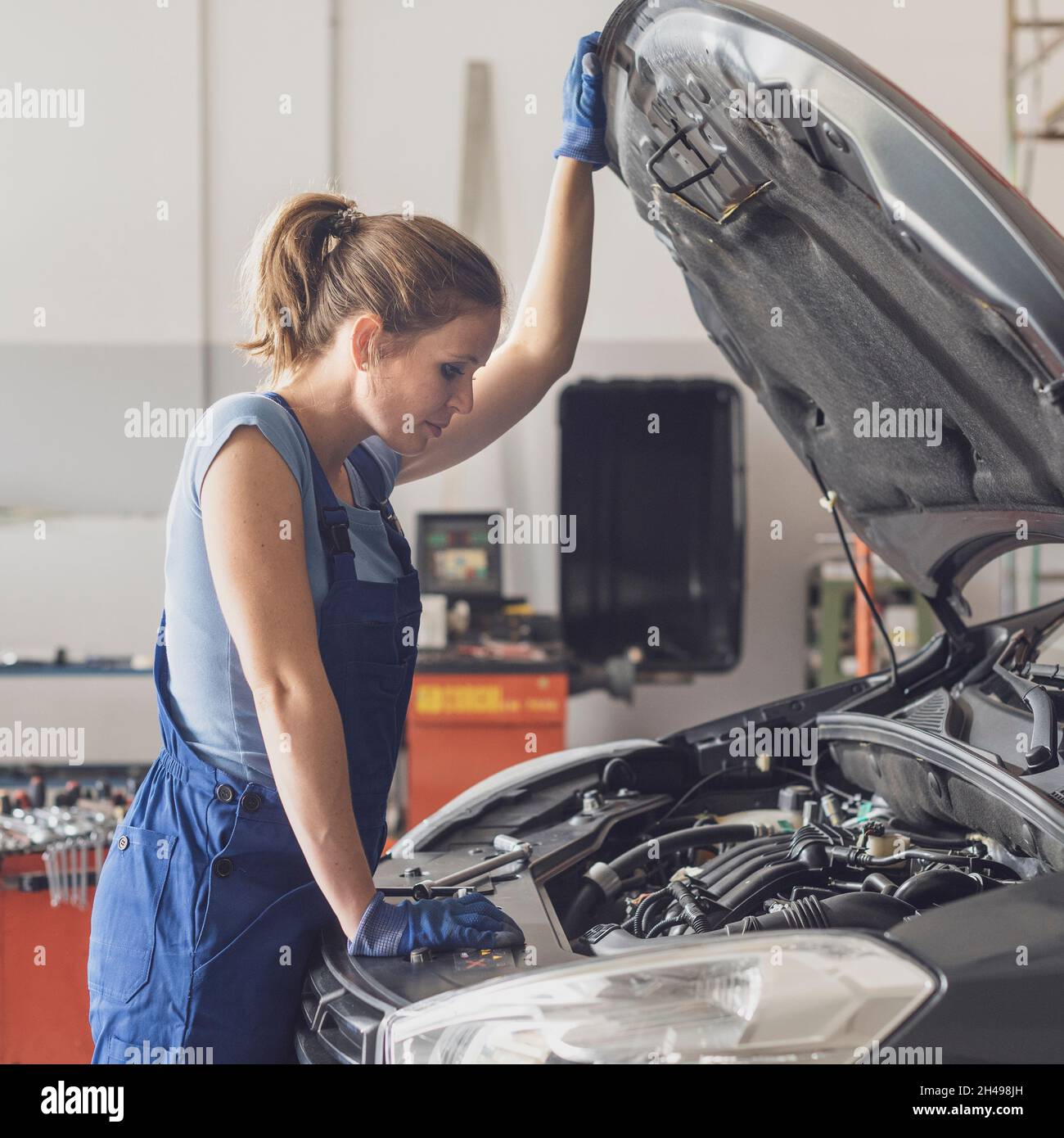 Confident female mechanic working in the auto repair shop, she is ...