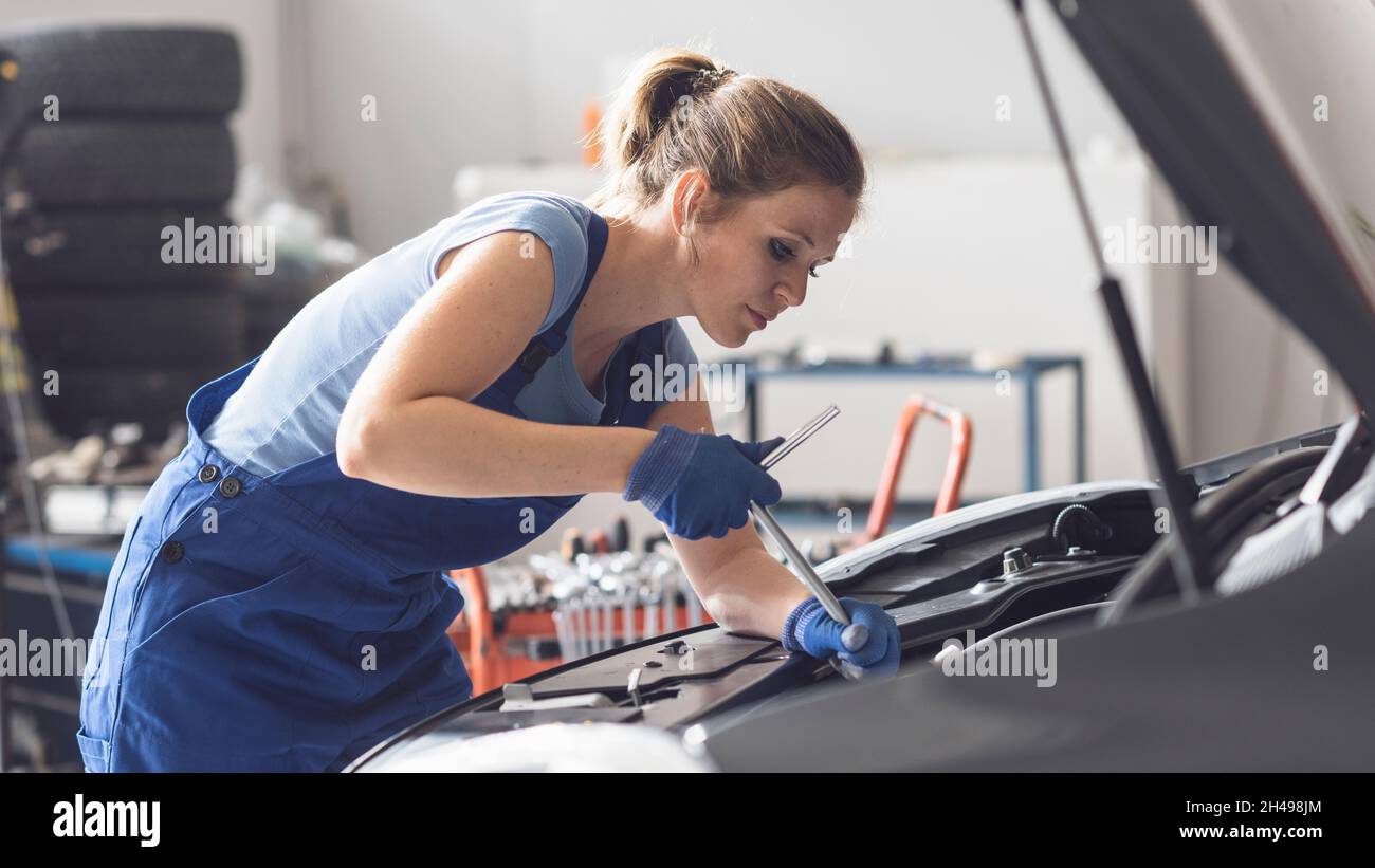 Professional female mechanic working in the car repair shop, she is ...