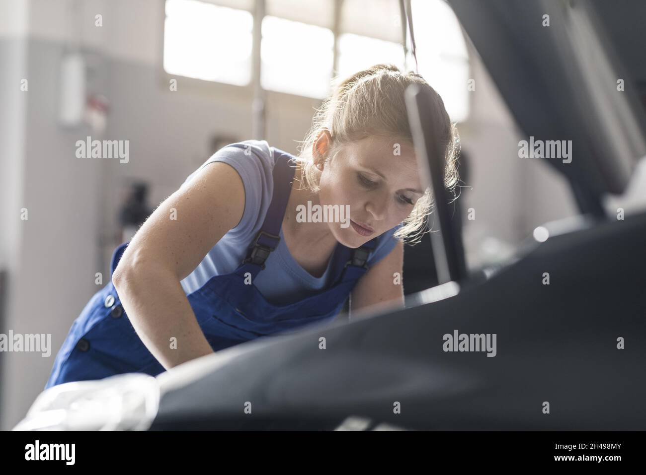 Confident female mechanic fixing a car in the auto repair shop Stock ...