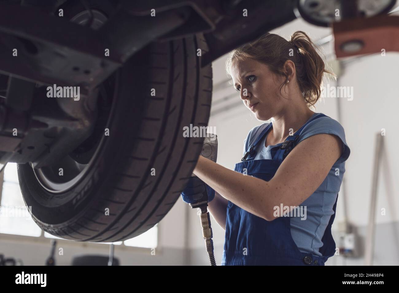 Professional female mechanic doing a wheel replacement in the auto ...