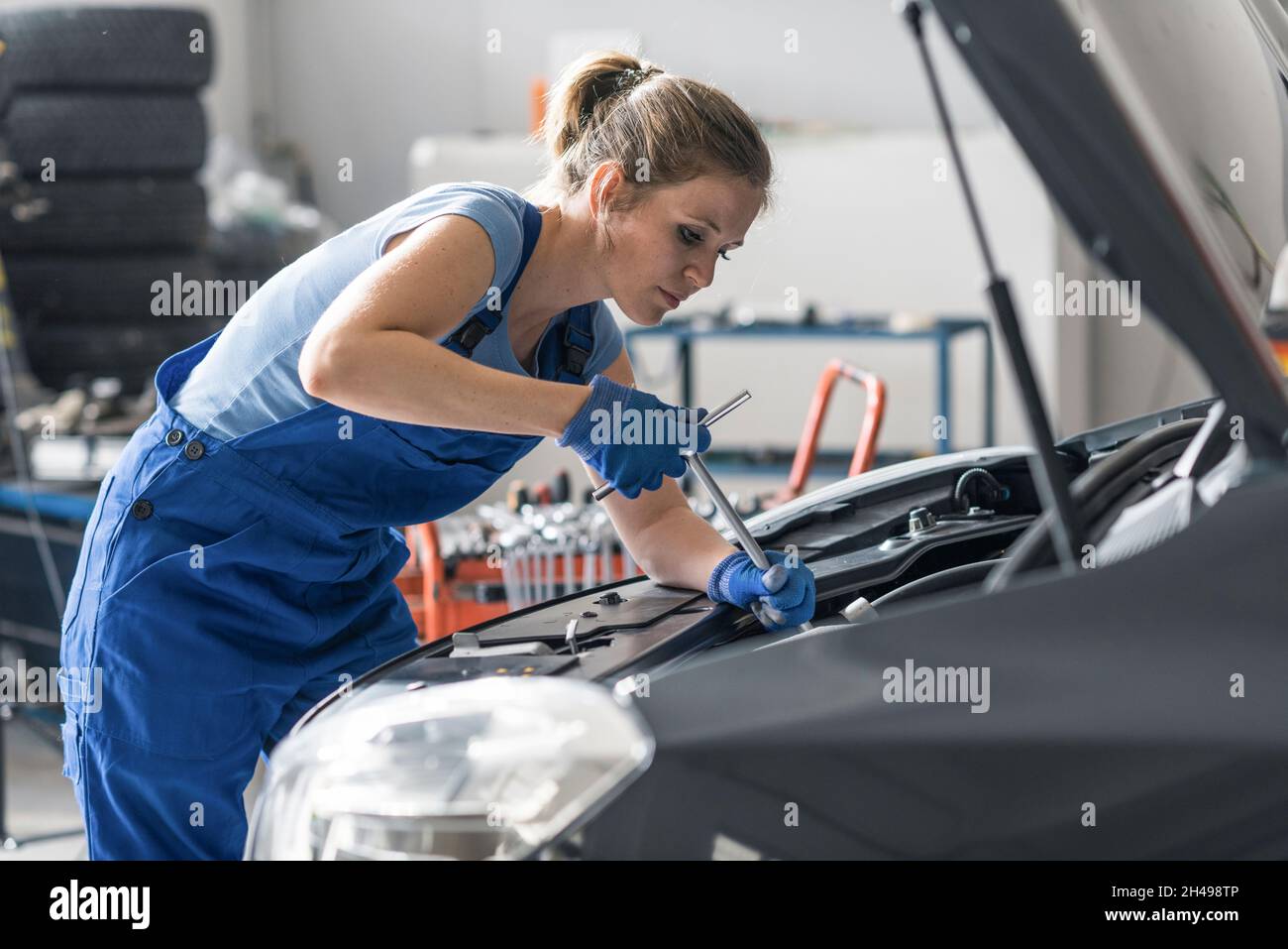 Professional female mechanic working in the car repair shop, she is ...