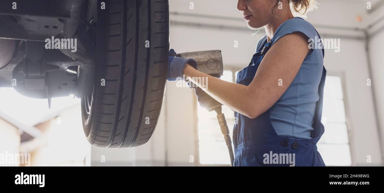 Professional female mechanic doing a wheel replacement in the auto ...