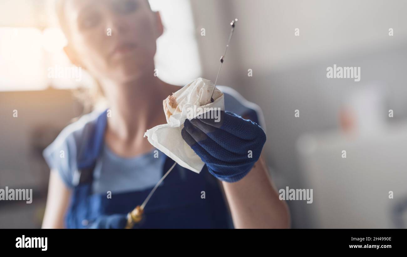 Professional female mechanic checking a car's engine oil using a dipstick Stock Photo - Alamy