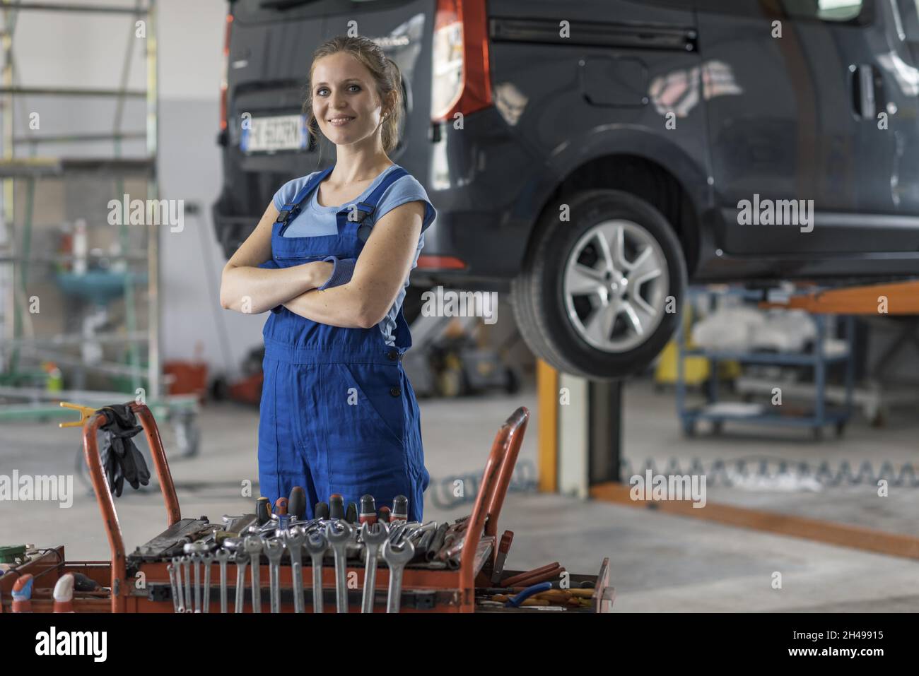 Confident female mechanic in the auto repair shop, she is posing with ...