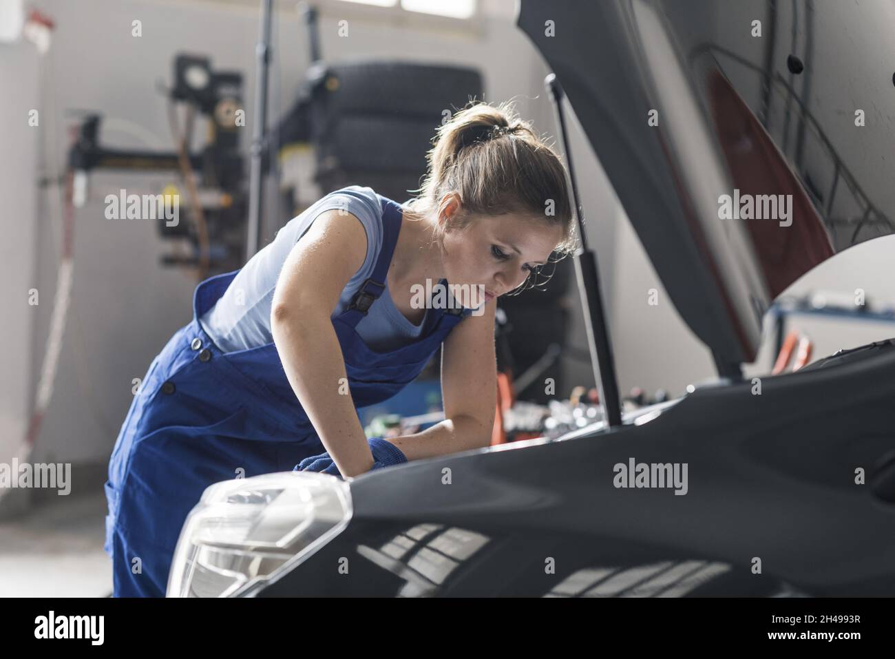 Confident female mechanic fixing a car in the auto repair shop Stock ...
