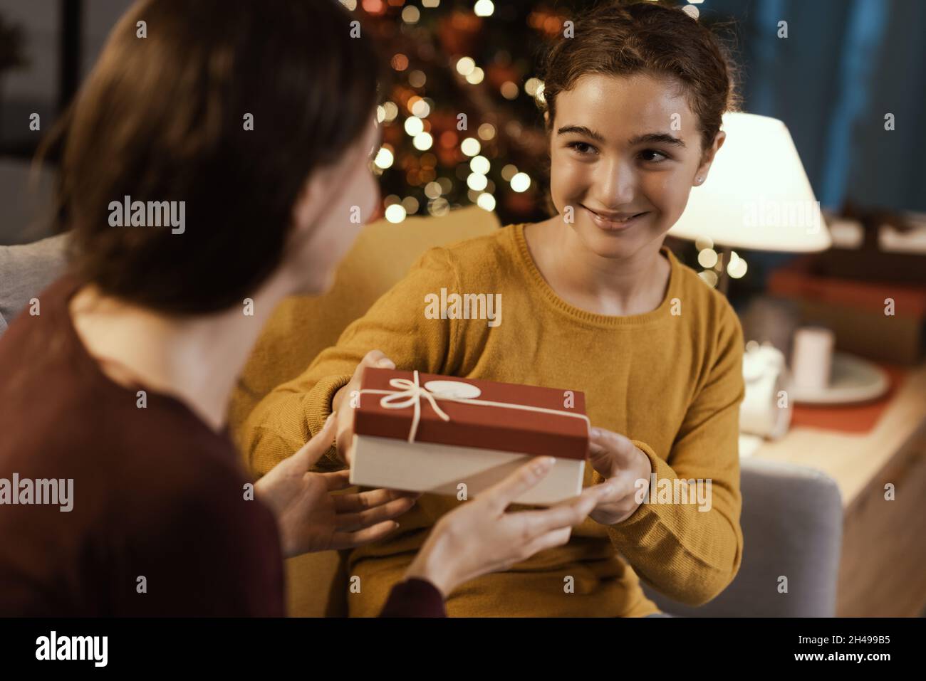Happy girl receiving a beautiful Christmas gift from her mother Stock ...