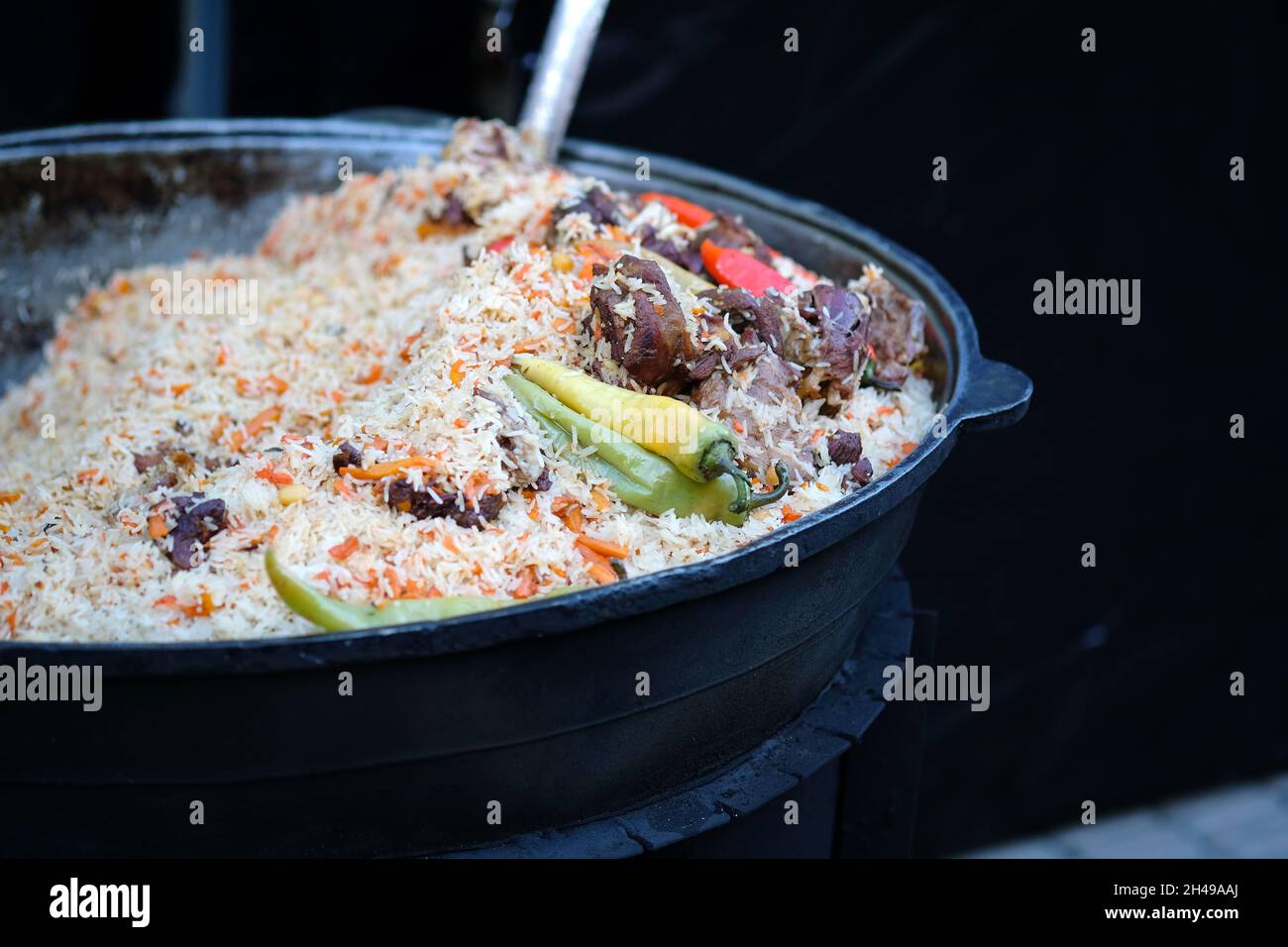 Rice with meat, carrots in a large cauldron. Pilaf with spices during ...