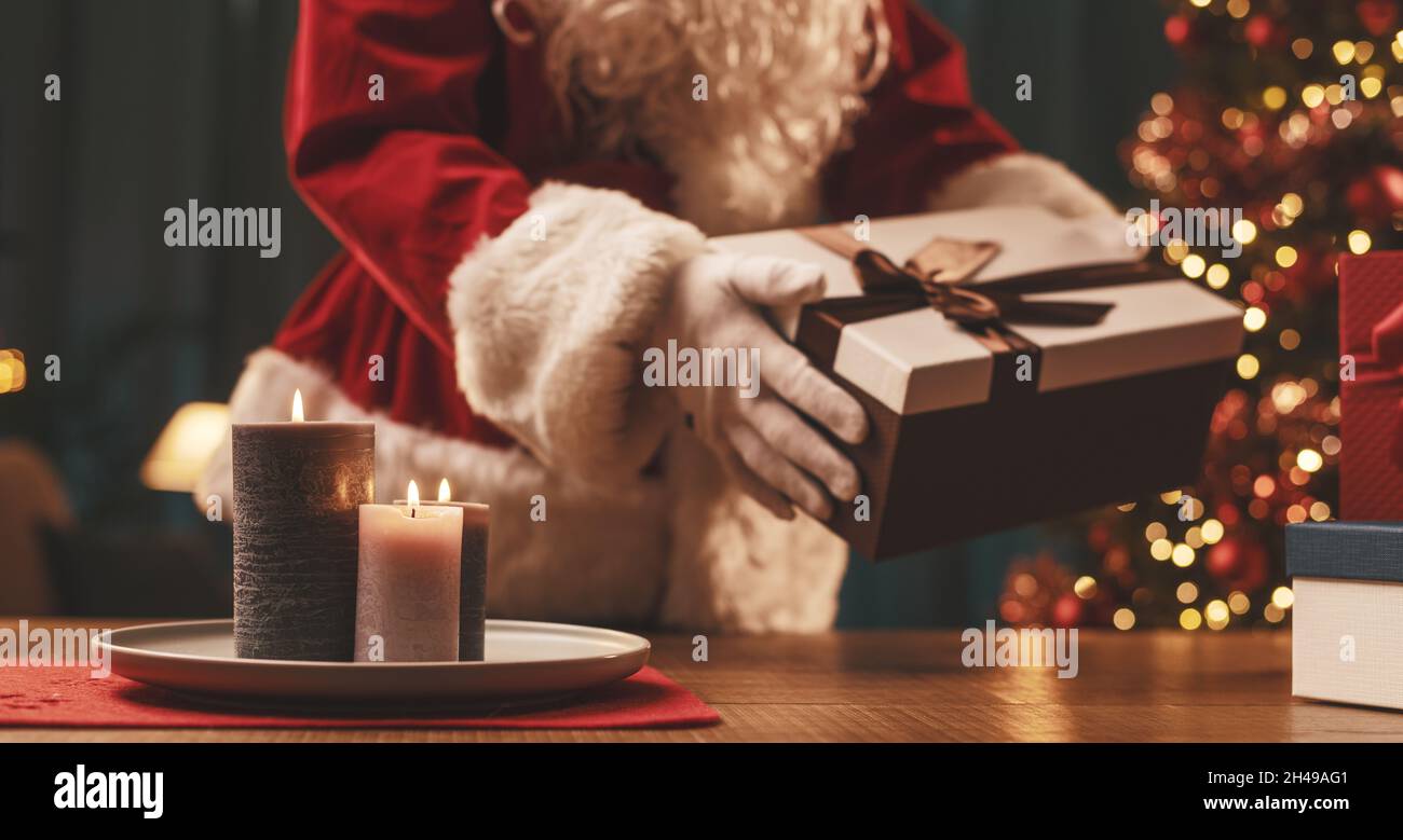 Santa Claus bringing gifts at home on Christmas Eve, he is holding a ...