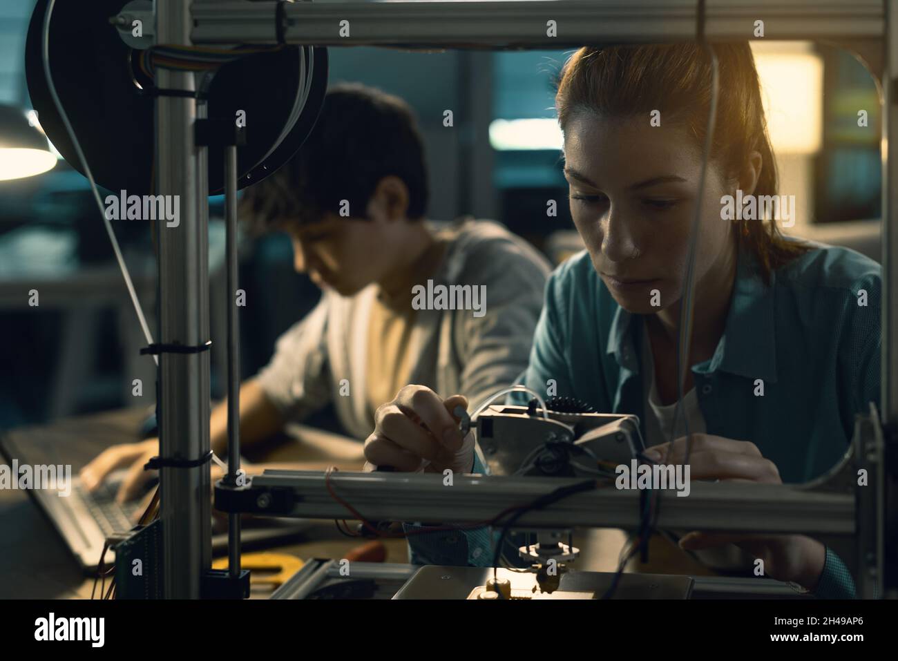 Smart students using a 3D printer and a laptop, engineering and ...