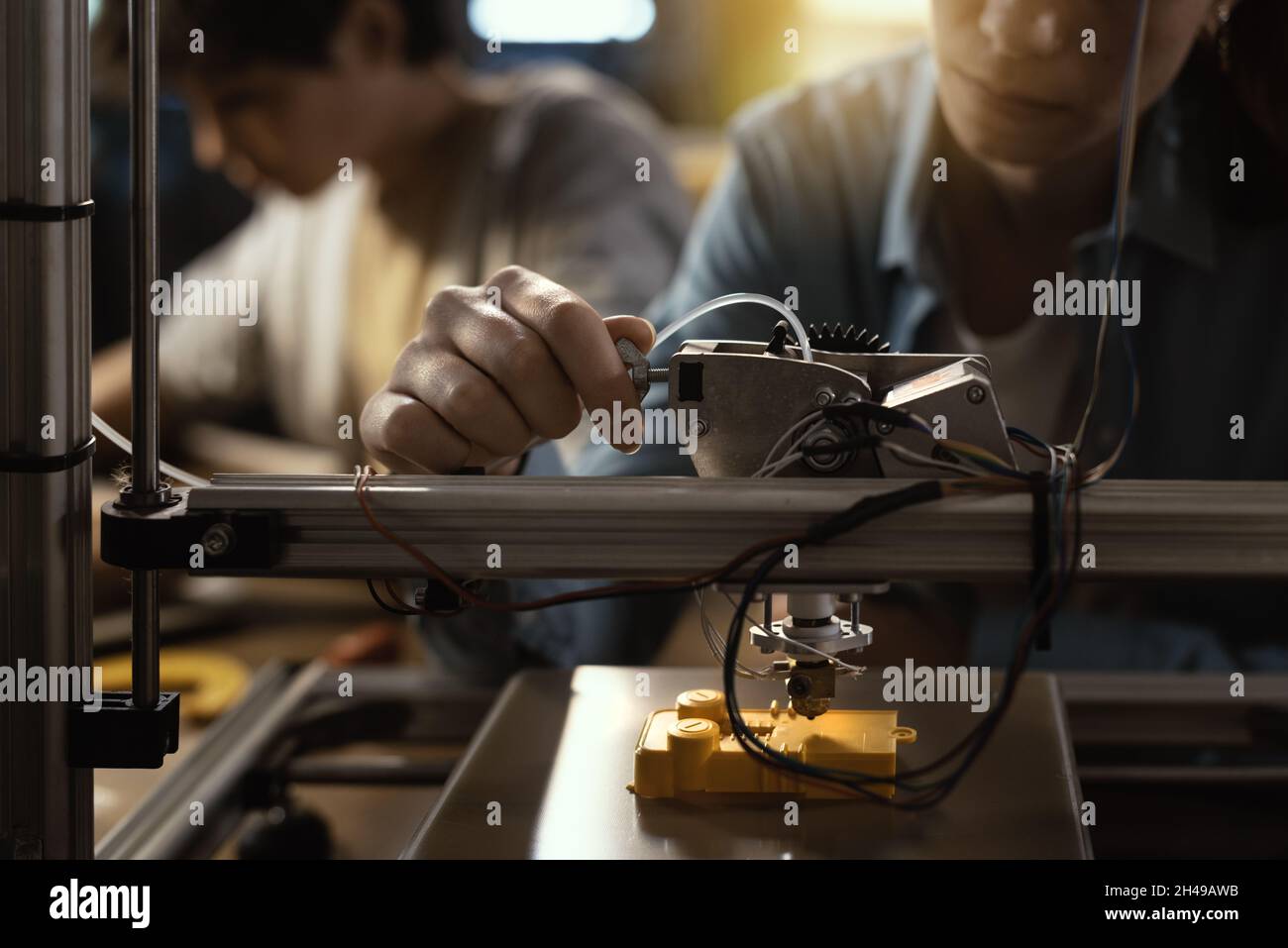 Smart students using a 3D printer and a laptop, engineering and ...