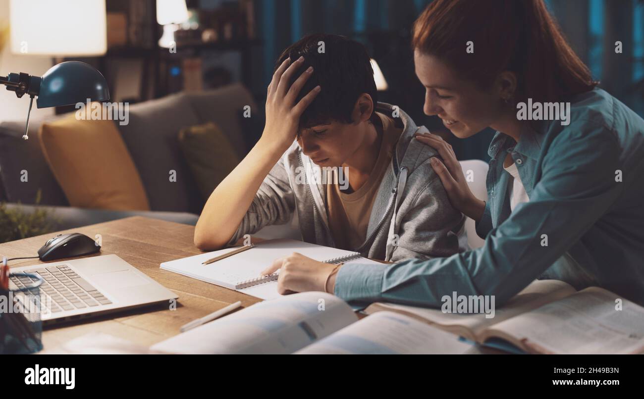 Caring sister helping her younger brother with his homework, he is ...