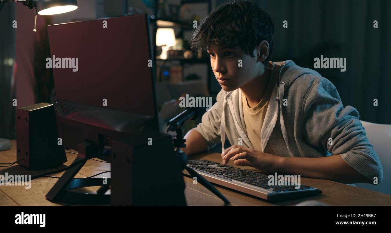 Boy connecting online at night and playing video games, entertainment ...