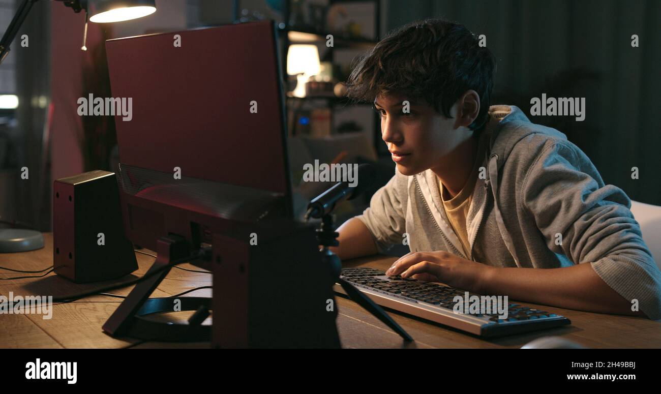 Boy connecting online at night and playing video games, entertainment ...