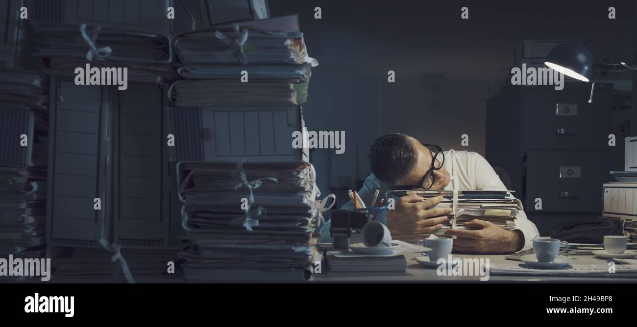 Stressed exhausted office worker sleeping at his office desk, he is ...
