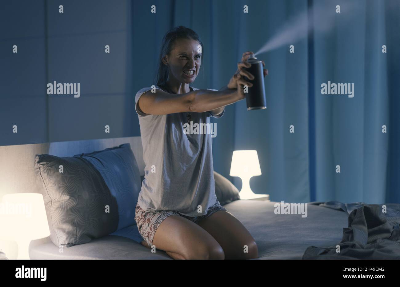 Angry woman spaying insectide in her bedroom, she is trying to kill ...