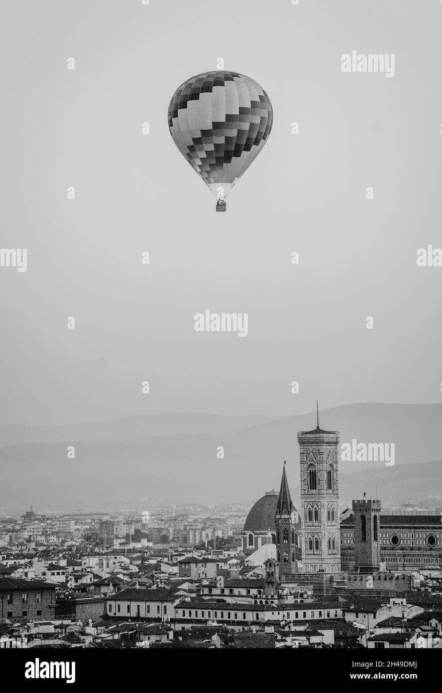 Vertical grayscale shot of a hot air balloon floating over Florence ...