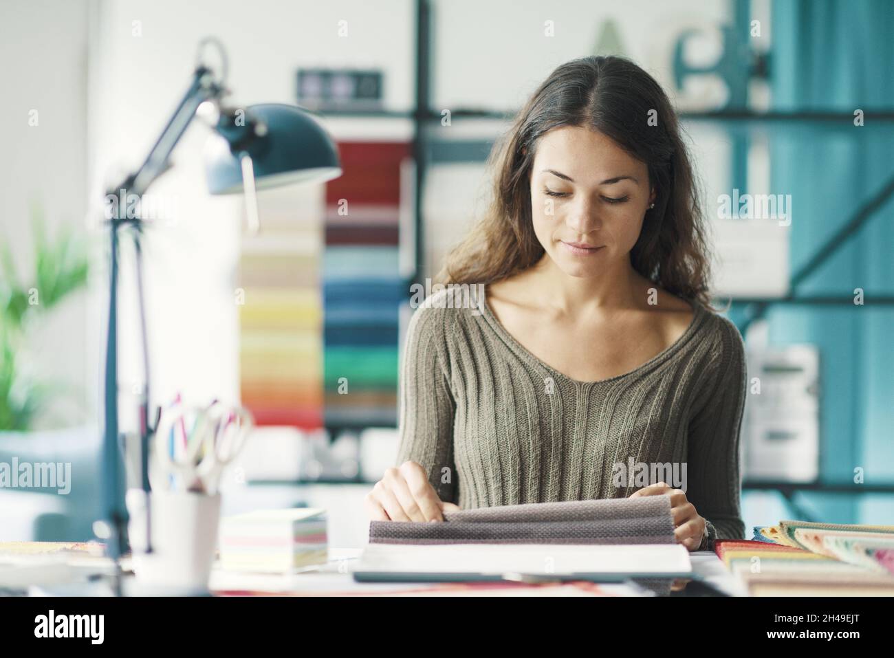 Young creative designer and decorator checking textile samples in her ...