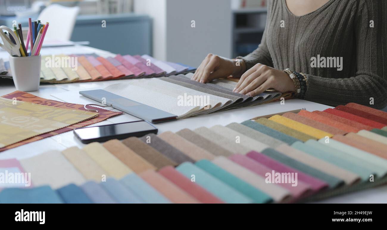 Woman sitting at desk and selecting fabric swatches, she is touching ...