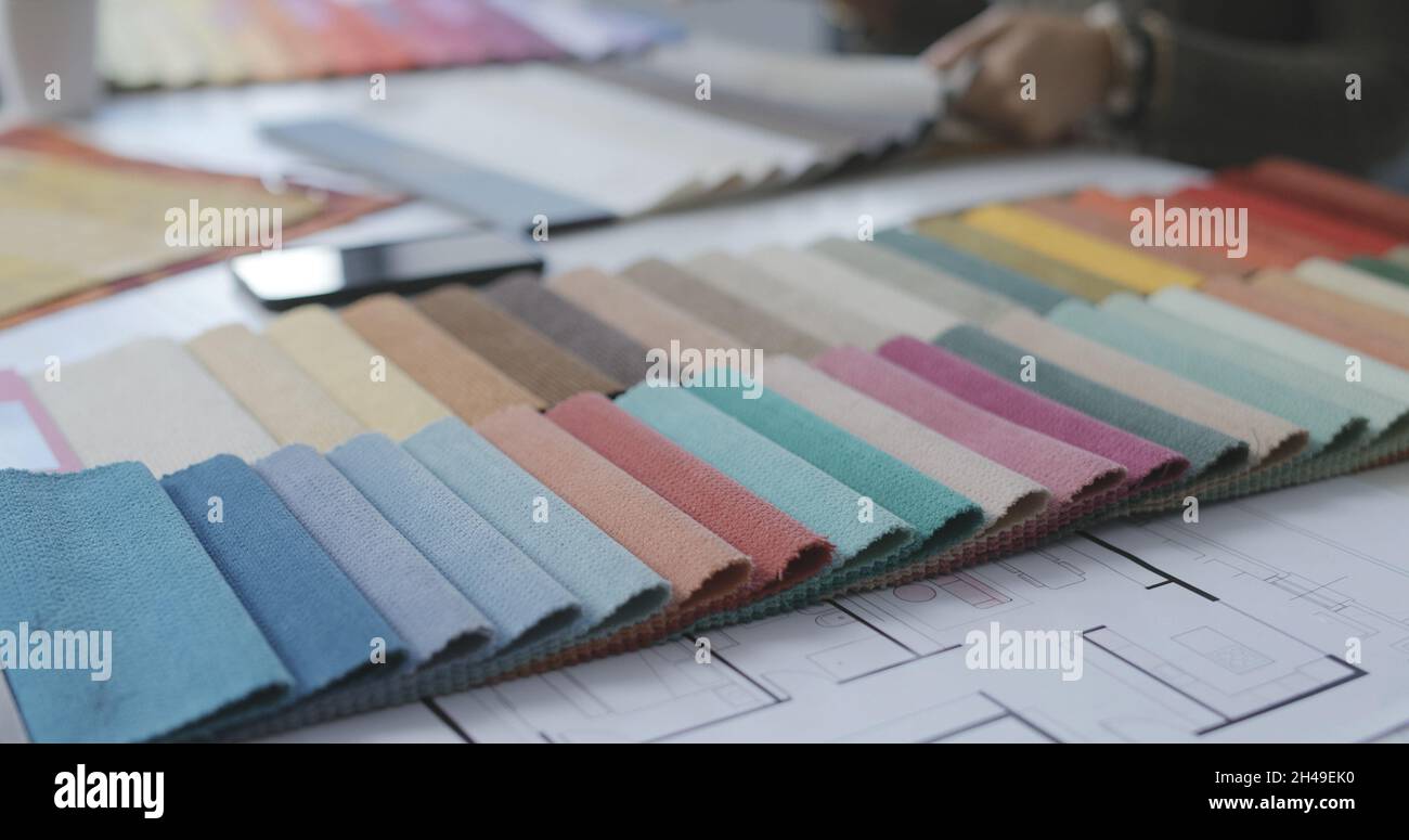 Woman sitting at desk and selecting fabric swatches, she is touching ...