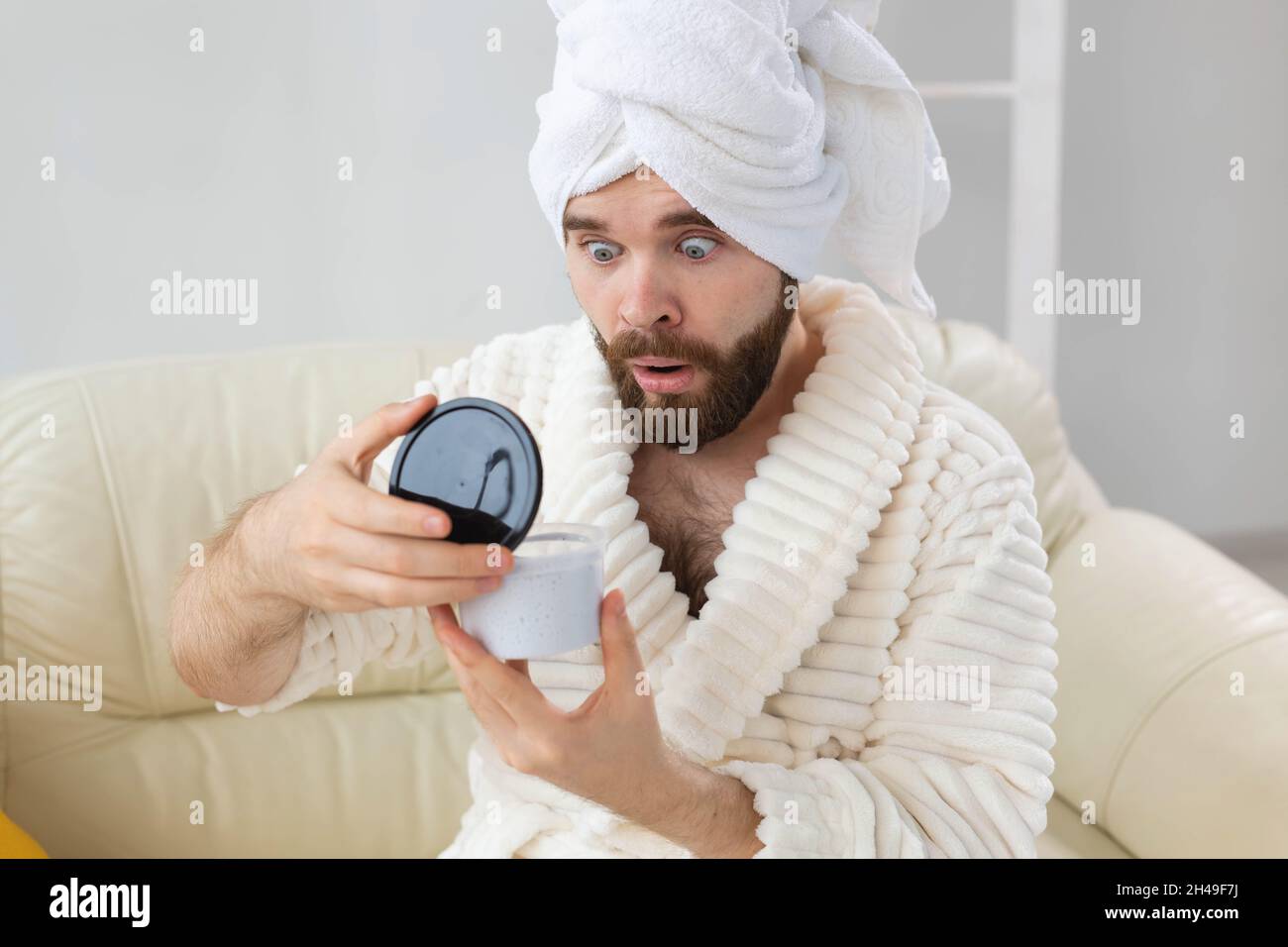 Portrait of man applying effective cream on his facial skin. Spa at ...