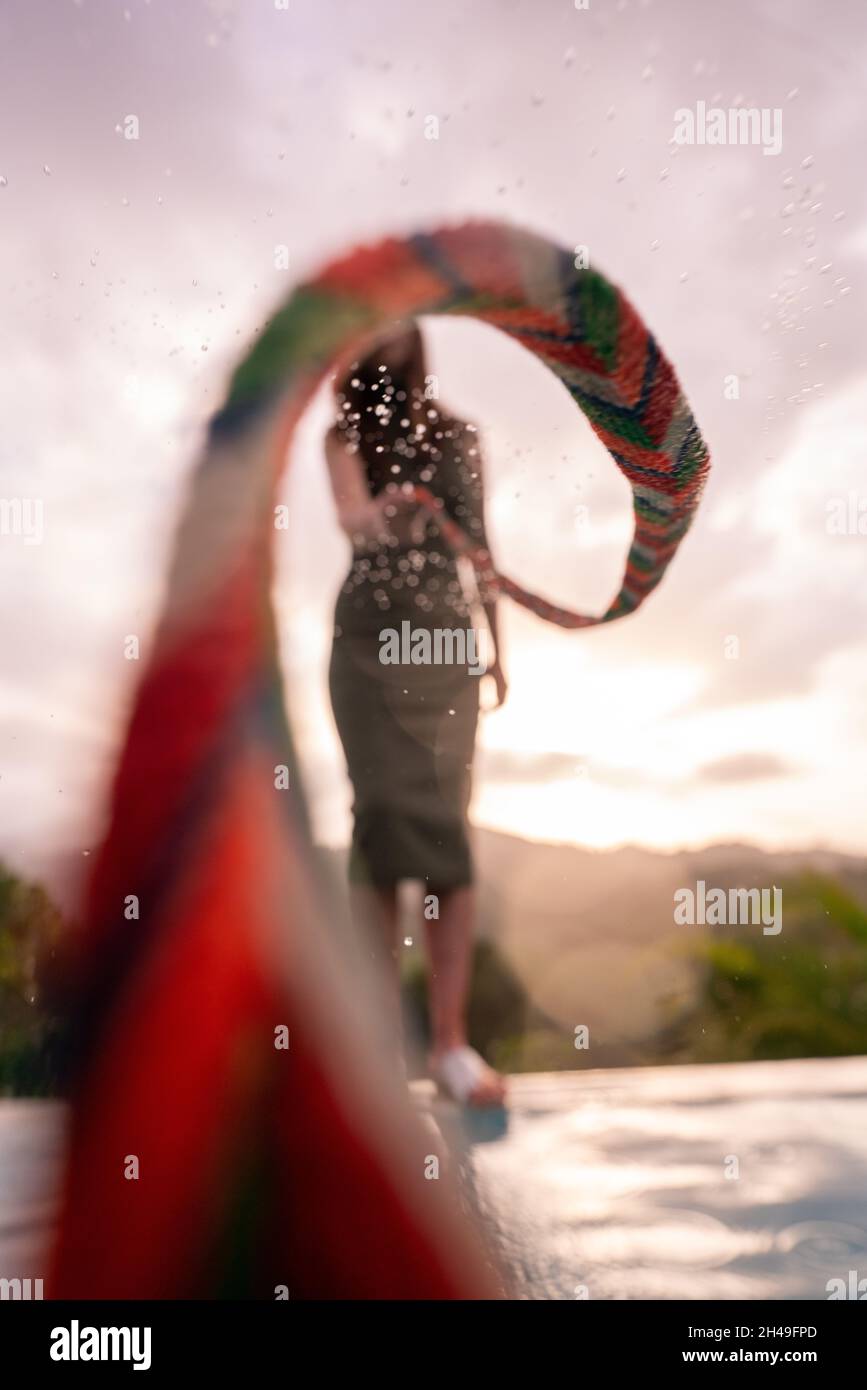 Selective of a colorful rope in the hand of a woman spinning it in the ...