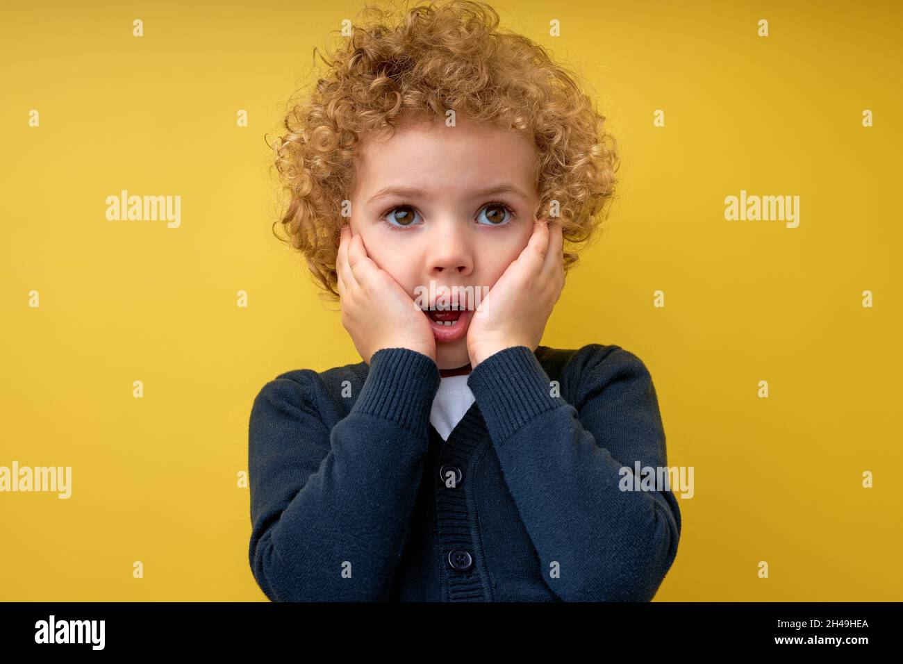 Little surprised child boy in shock, touching cheeks, stand with widely ...