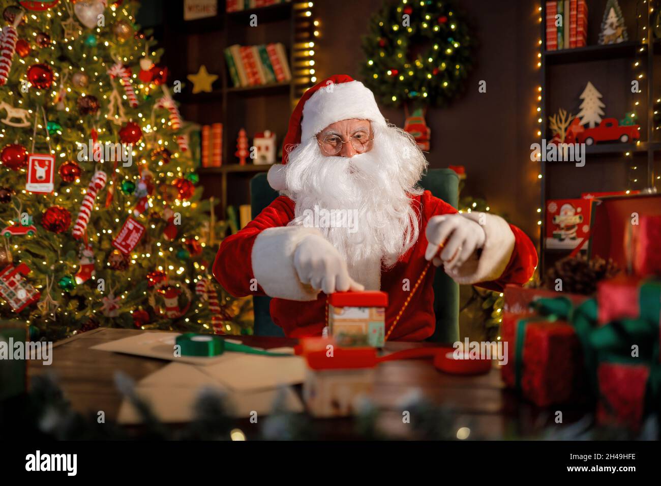 Santa Clause is preparing gifts for children for Xmas while sitting at ...
