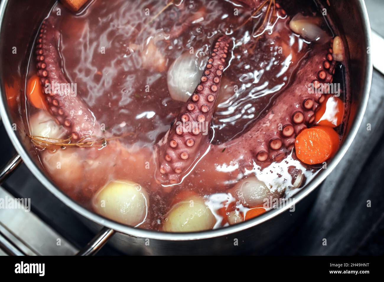 Whole octopus boiling in the the pot filled with water and vegetables ...